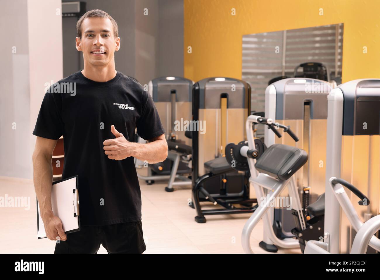 Portrait of personal trainer with clipboard in modern gym Stock Photo ...