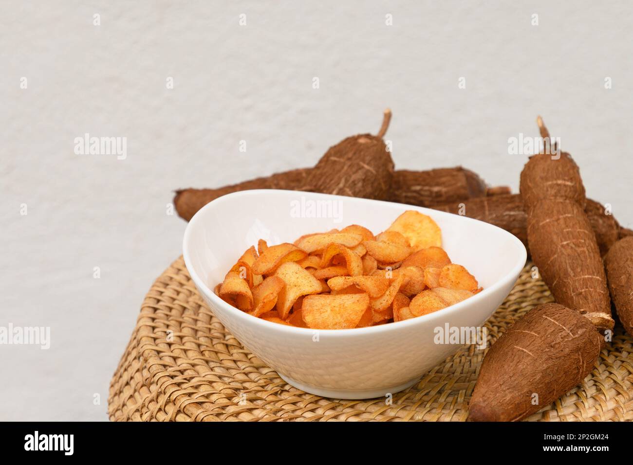 Organic manioca or cassava chips in bowl and tapioca tuber. Indonesia ...