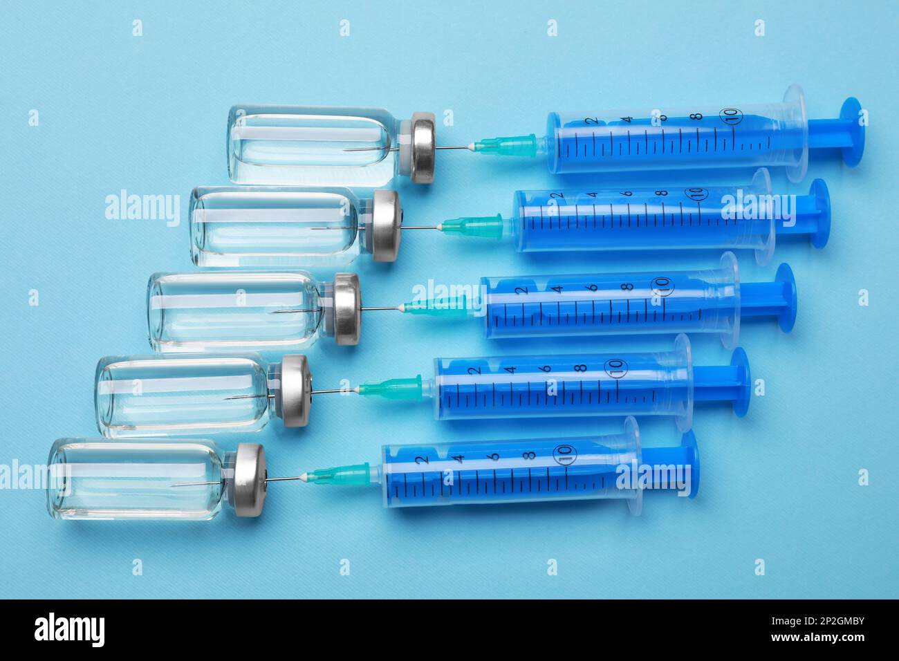Disposable syringes with needles and vials on light blue background ...