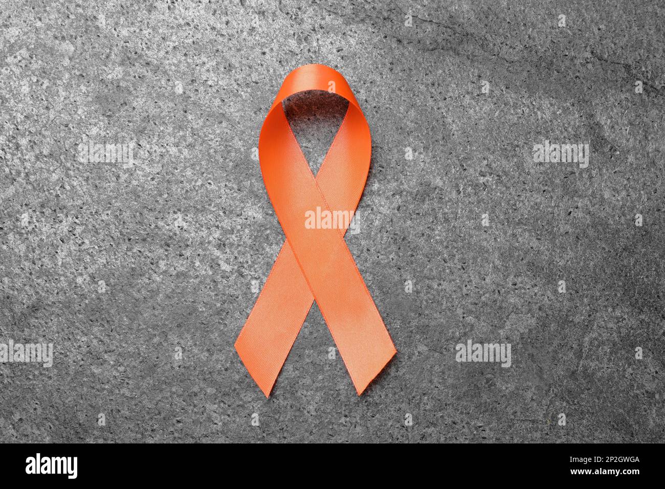 Orange ribbon on grey table, top view. Multiple sclerosis awareness ...
