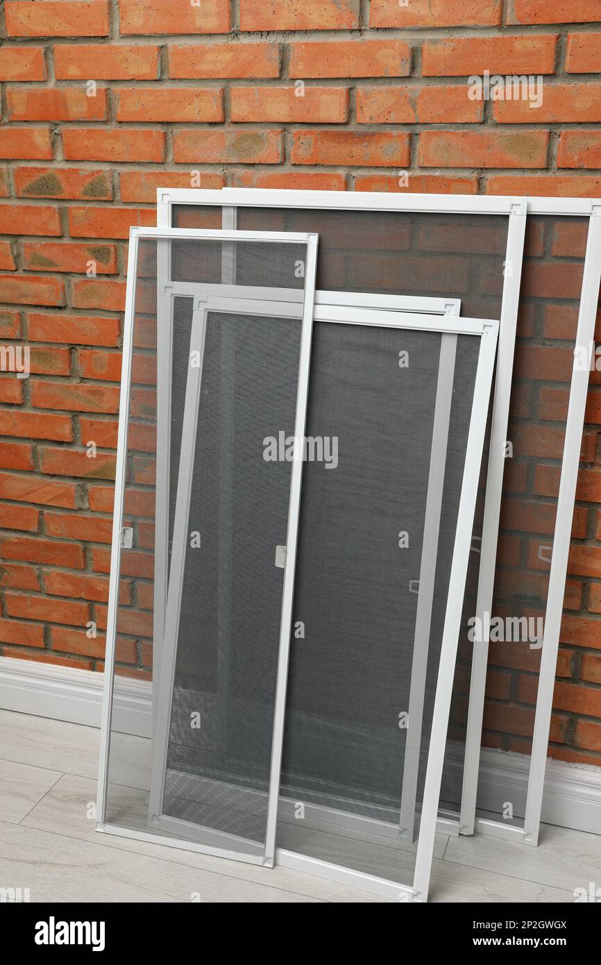 Set of window screens near brick wall indoors Stock Photo - Alamy
