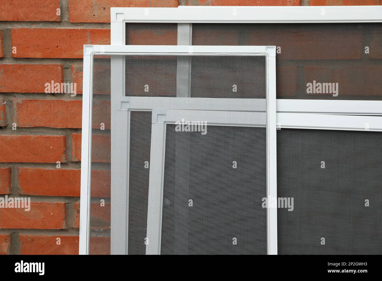 Set of window screens near brick wall Stock Photo - Alamy