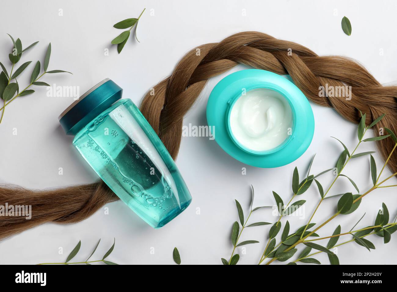 Natural cosmetic products, green leaves and hair braid on white ...