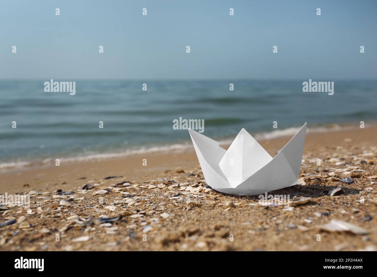 White paper boat on sandy beach near sea, space for text Stock Photo ...