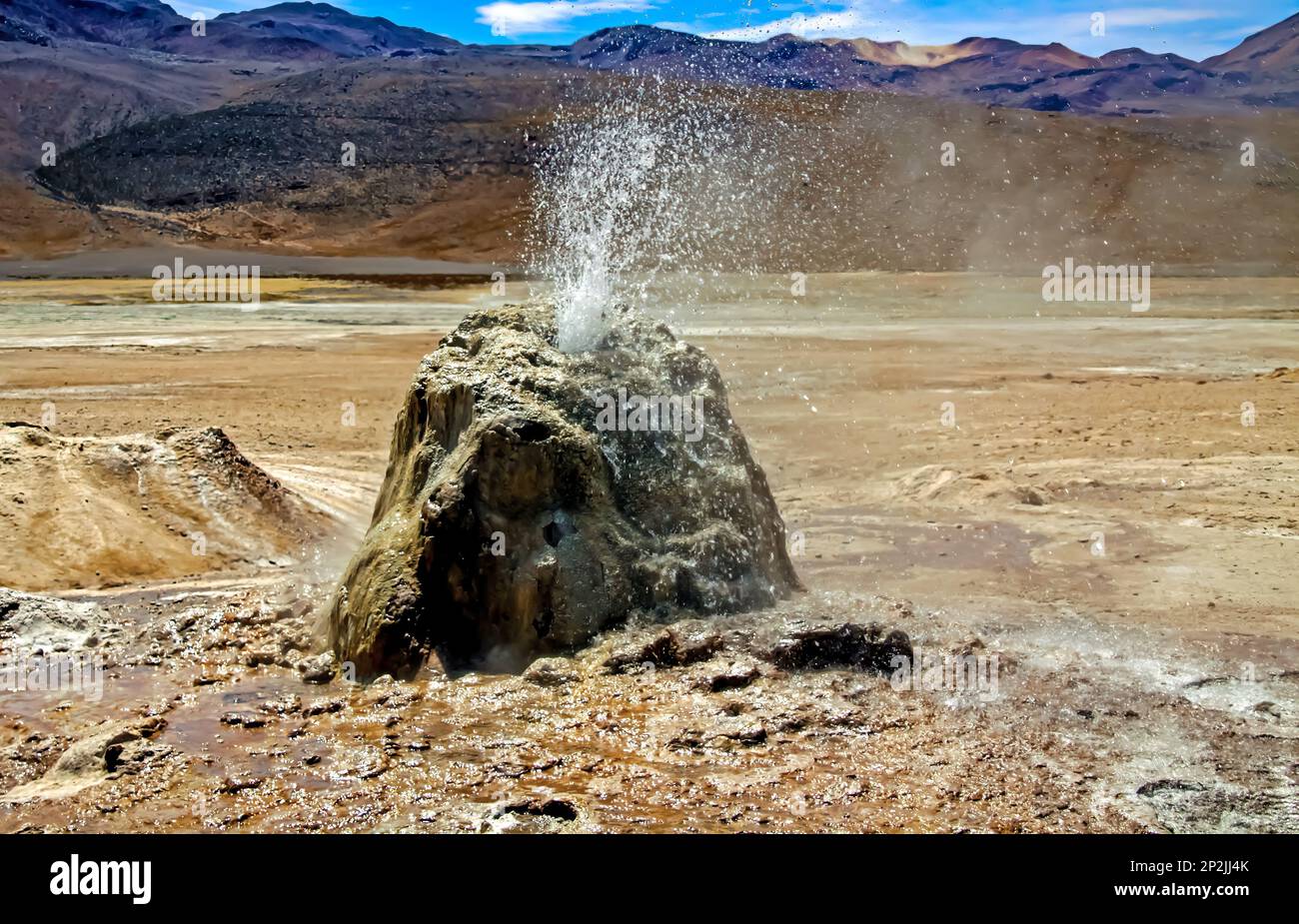 Close up geyser cone rock spitting hot water in dry arid barren valley ...
