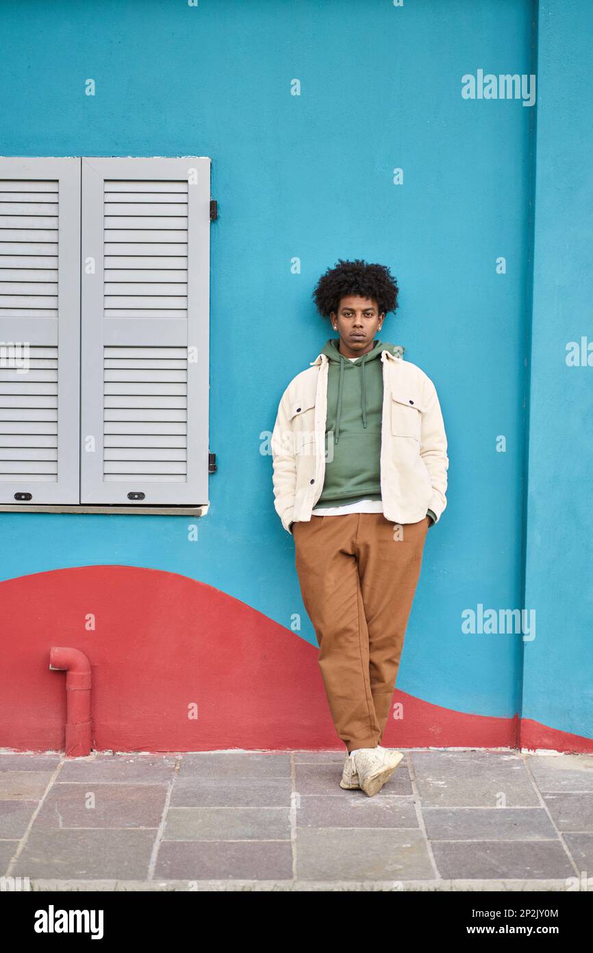Cool stylish young gen z hipster African American guy at blue wall ...