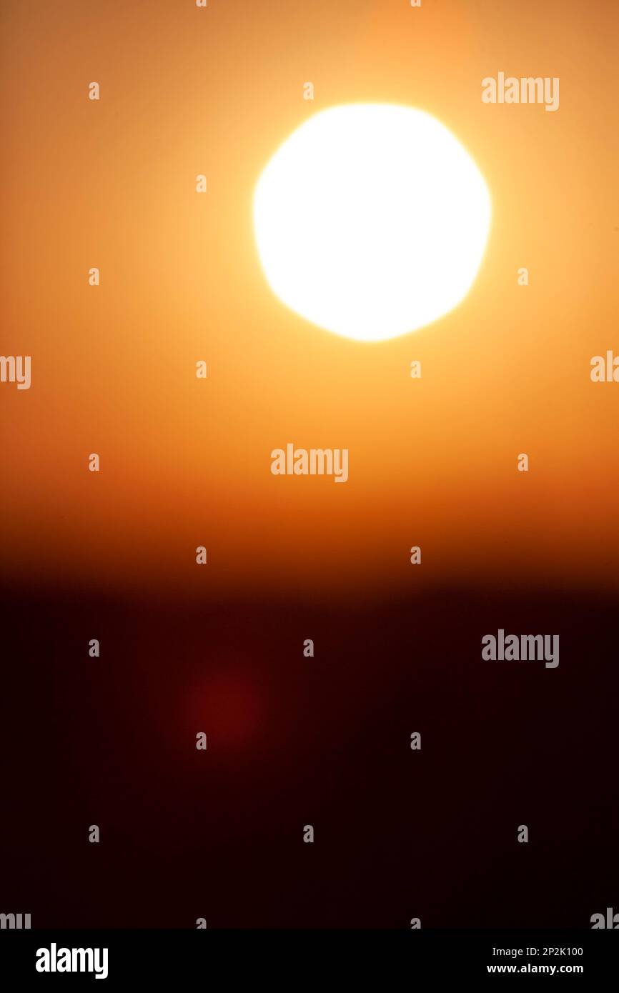 Blurry photo of the sun at sunset. Orange and dark vertical background ...