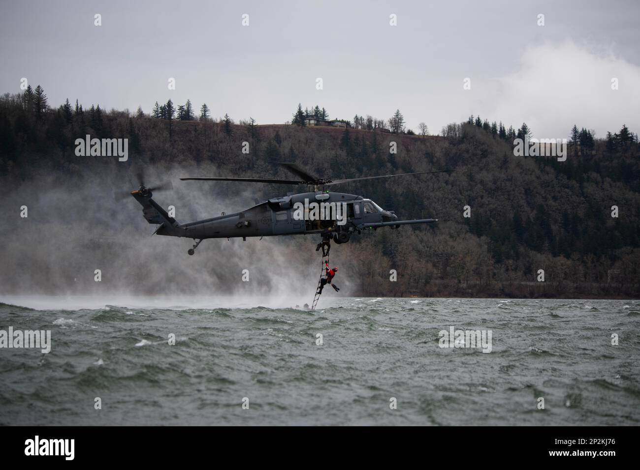 304th Rescue Squadron pararescuemen ascend a rope ladder connected to a ...