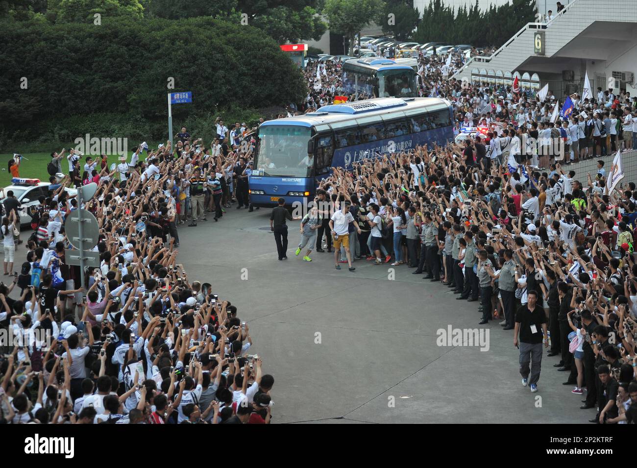 A crowd of football fans watch the arrival of buses carrying players of ...