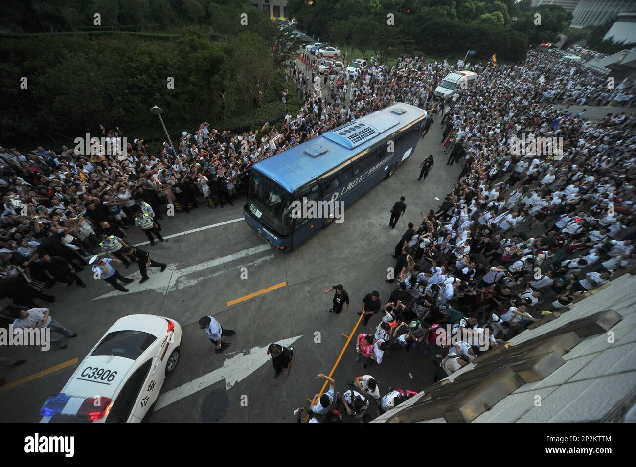 A crowd of football fans watch the arrival of a bus carrying players of ...