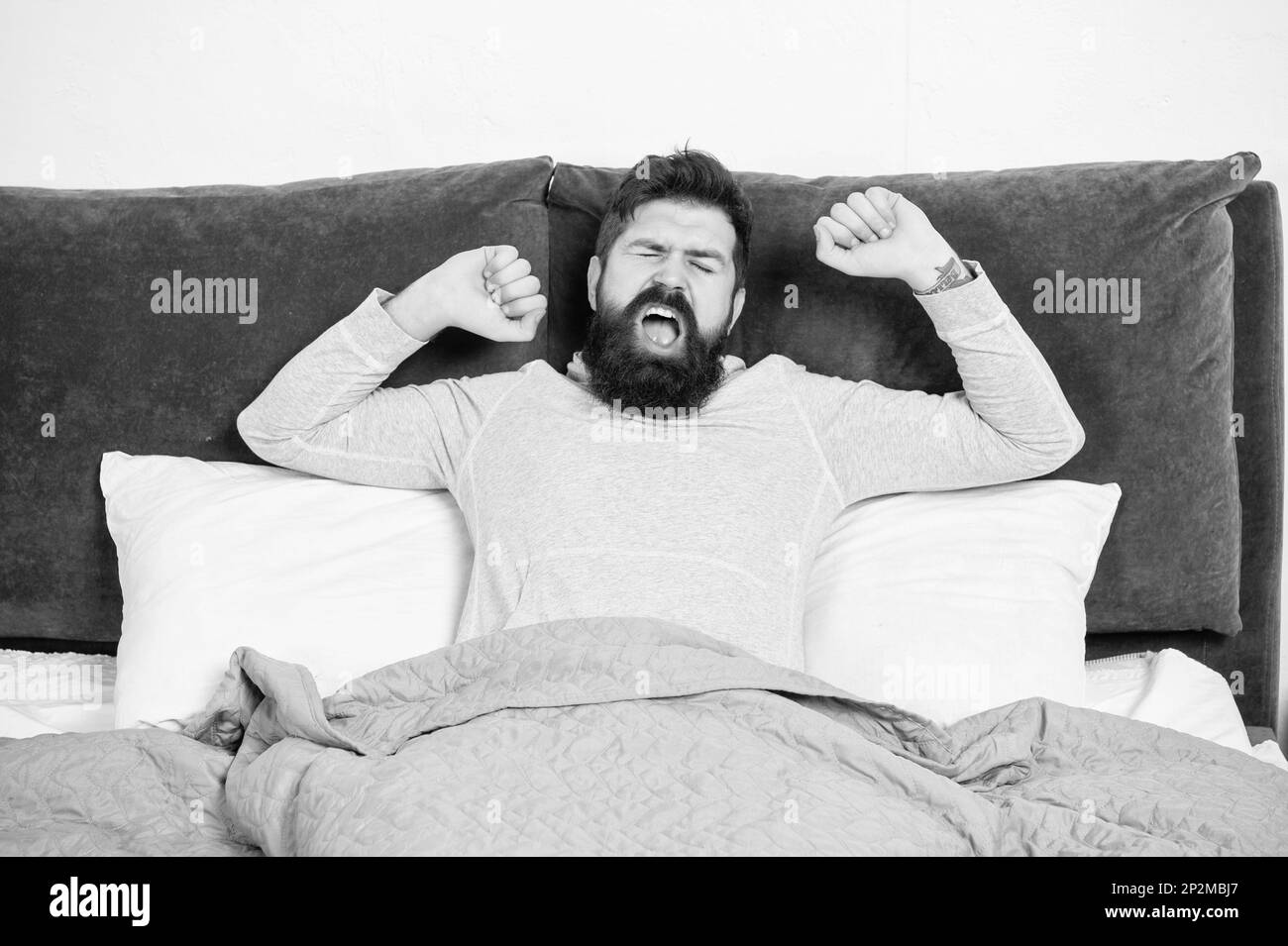 Sleepy man yawning and stretching in bed waking up after sleep, morning ...