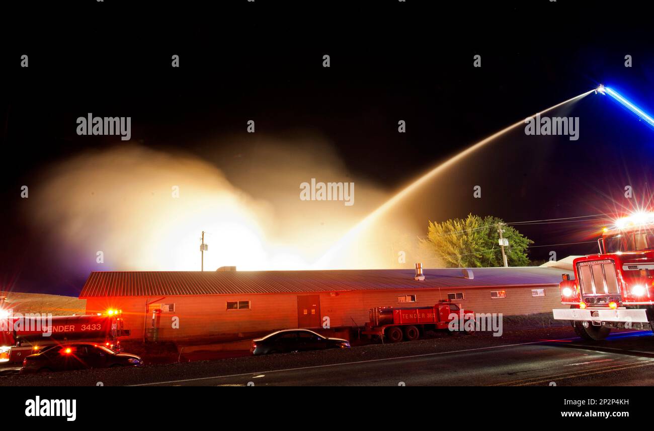Firefighters use an aerial ladder and hose to battle a fire, Wednesday ...
