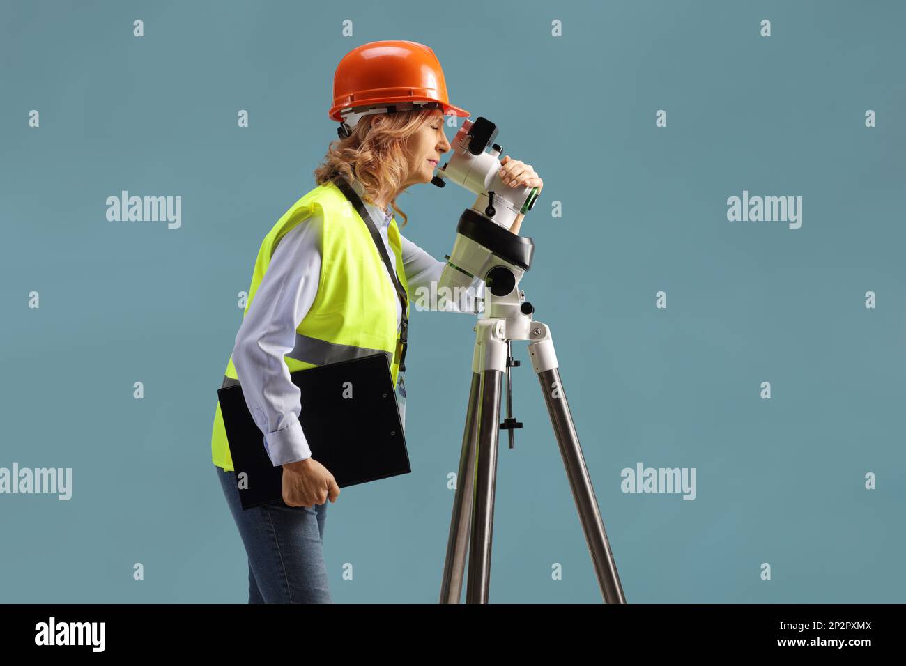 Profile shot of a female geodetic surveyor working with a measuring ...
