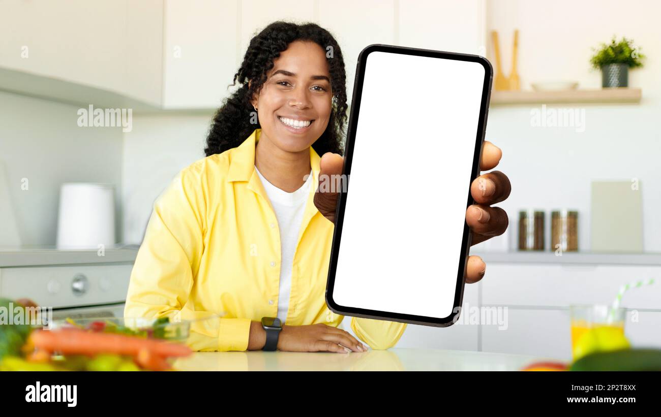 Black Smiling Female Showing Big Blank Smartphone While Cooking In ...