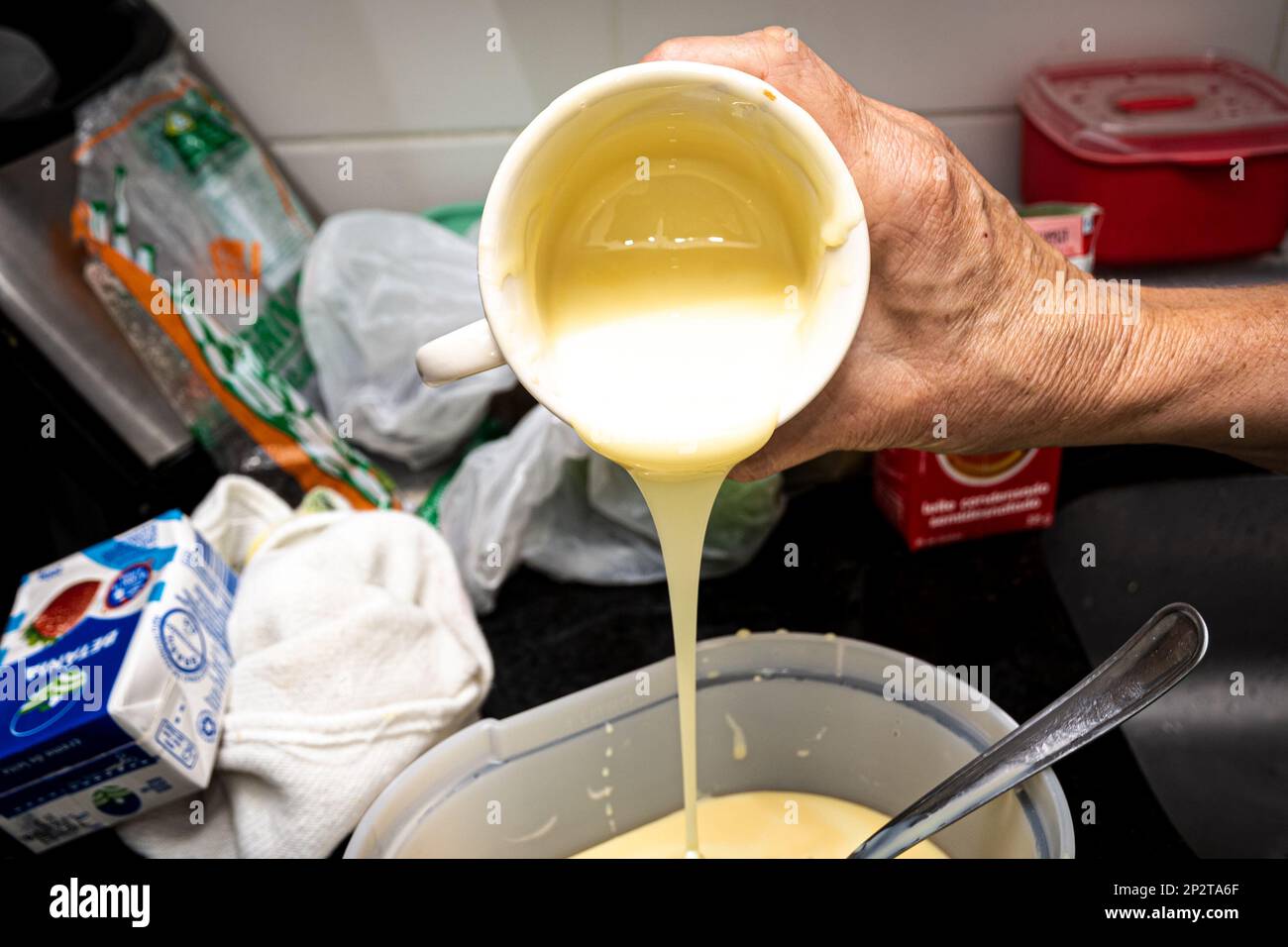 Cream being poured into a plastic container for making cheesecake ...