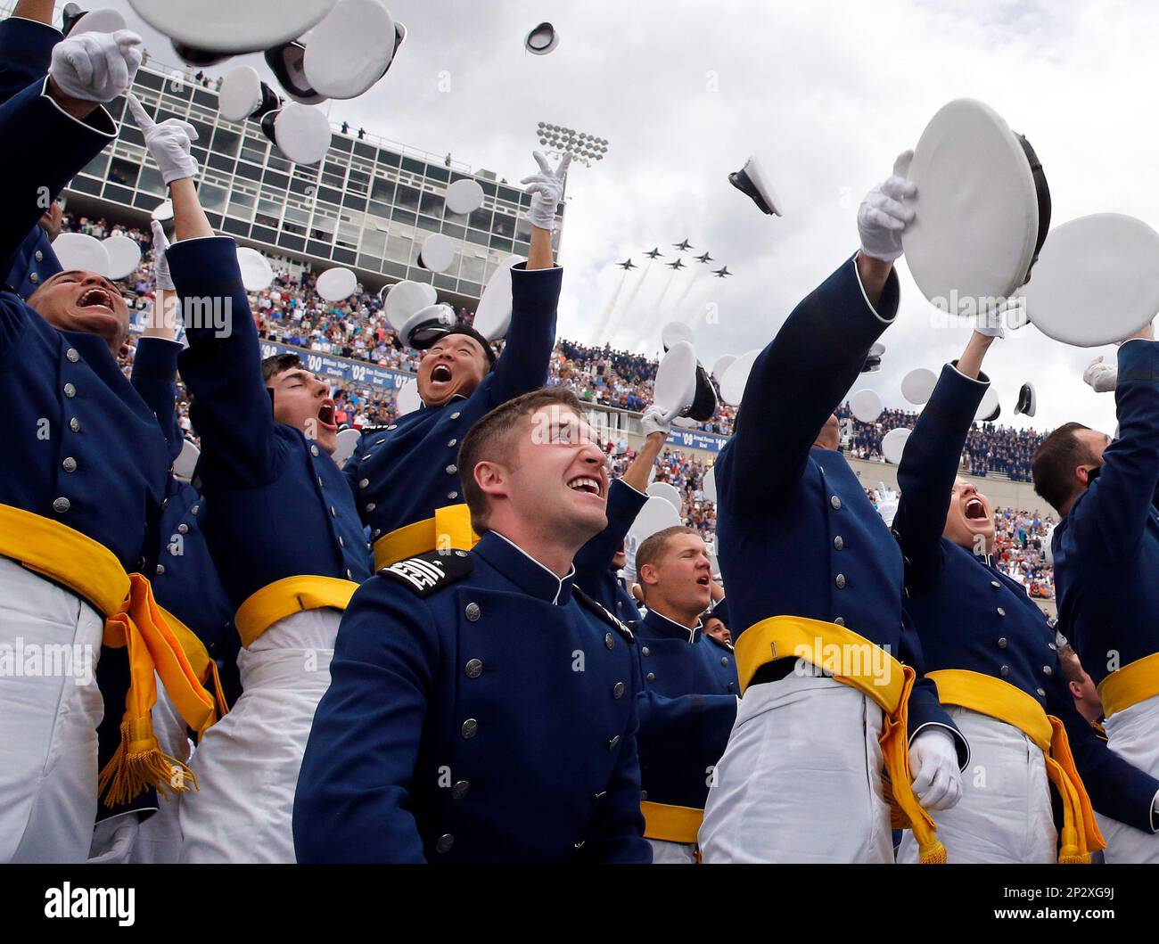 Air Force Academy graduates throw their caps into the air as F-16 jets ...