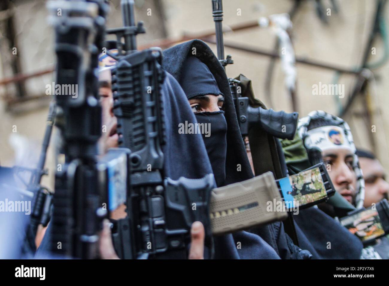Masked Palestinian gunmen from the Balata battalion hold their weapons ...