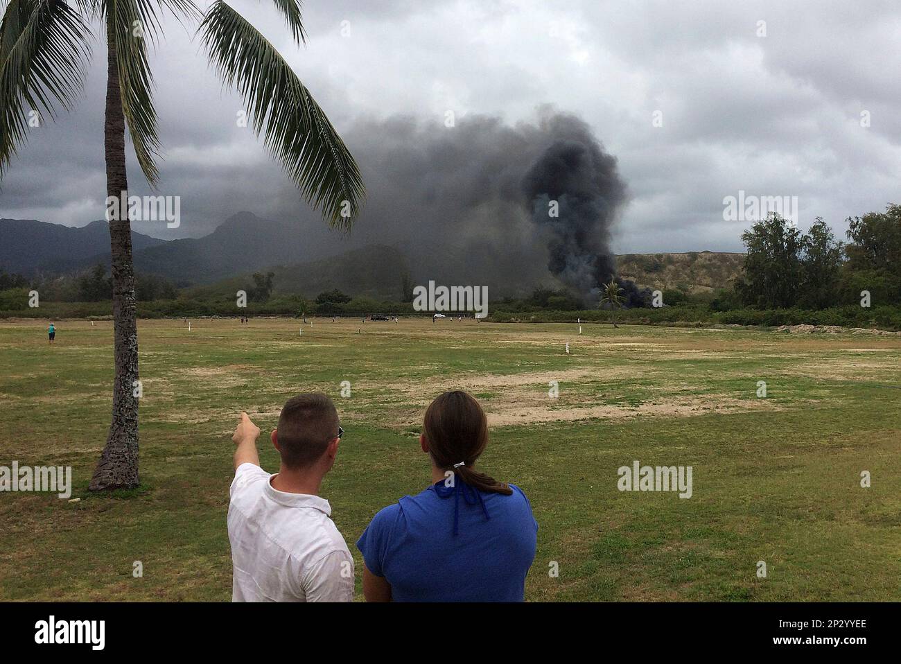 In this May 17, 2015 photo, a man and woman look toward smoke rising ...