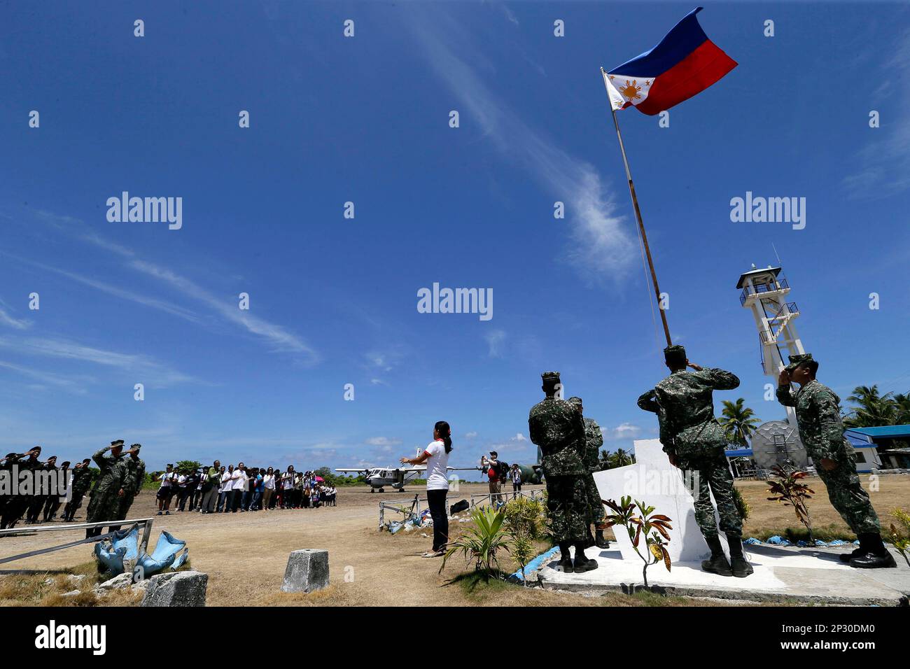 A Filipino resident, center, and soldiers conduct a flag raising ...