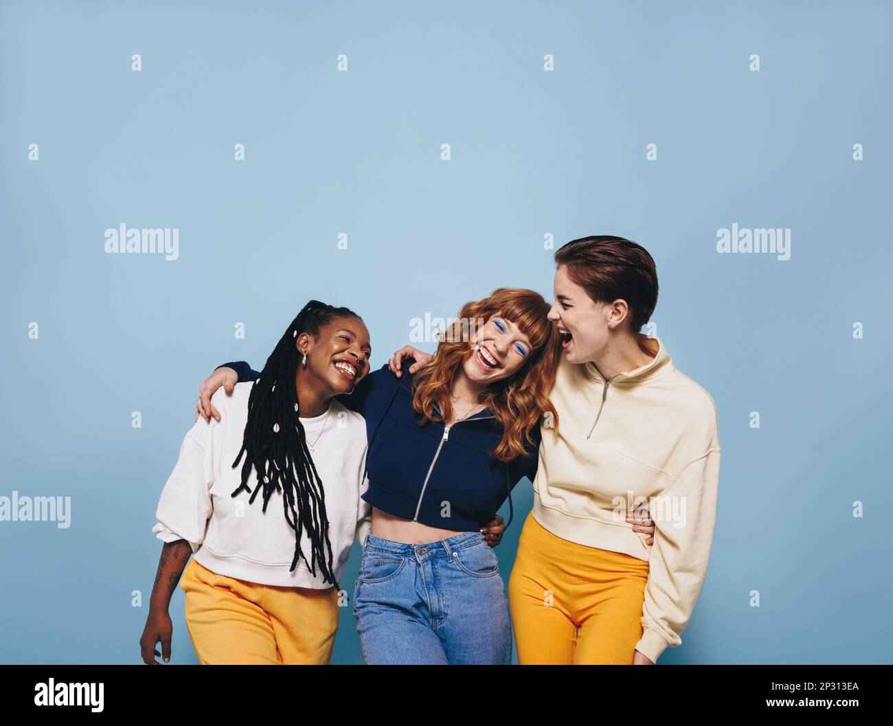 Multicultural female friends laughing and having fun while embracing ...