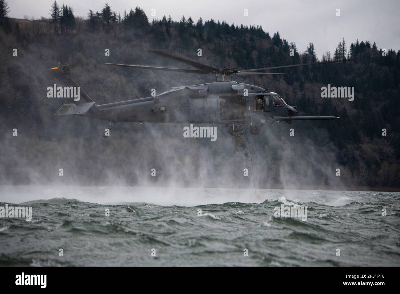 304th Rescue Squadron pararescuemen ascend a rope ladder connected to a ...
