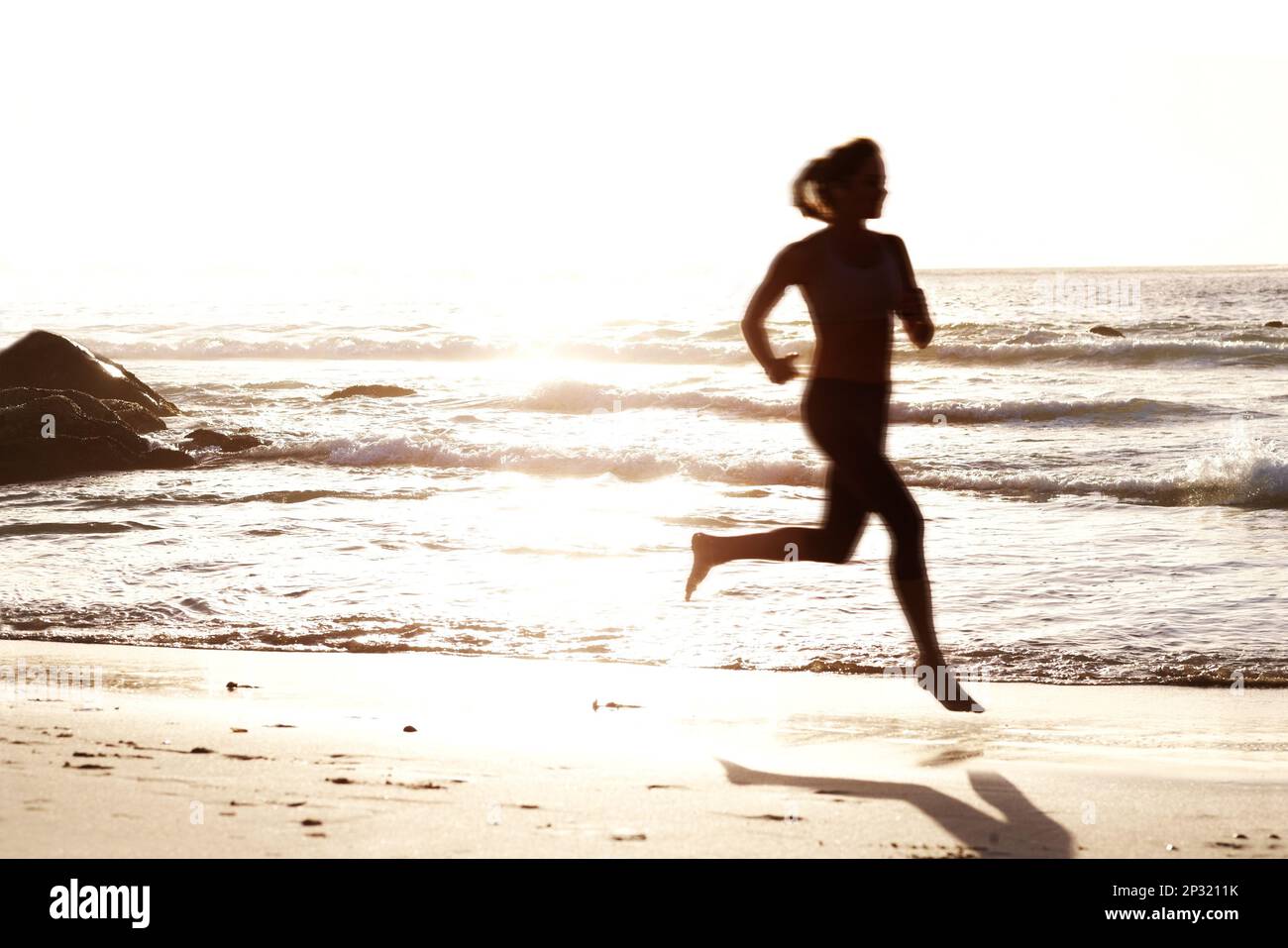 Young female running on beach during sunset. Portrait of a young female ...