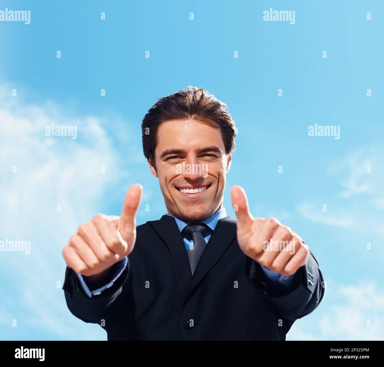 Smart business man with thumbs up with copyspace against sky. (Note to ...