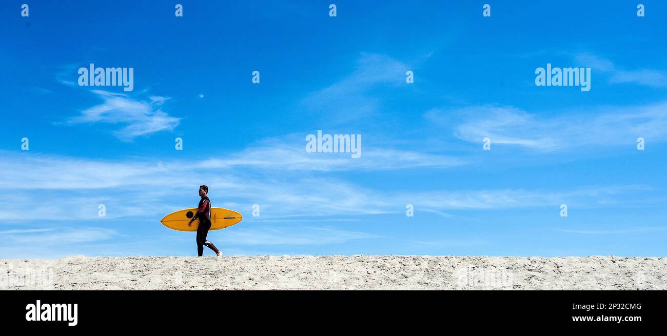 A surfer walks along the beach near the Oakley Lowers Pro surf contest ...