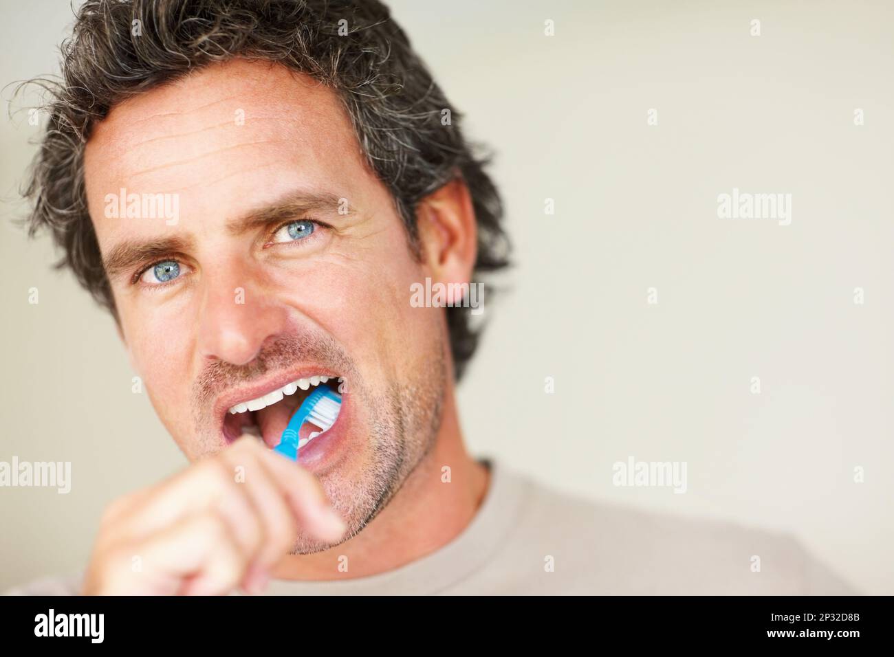 Morning routine. Closeup of smart middle aged man brushing his teeth ...