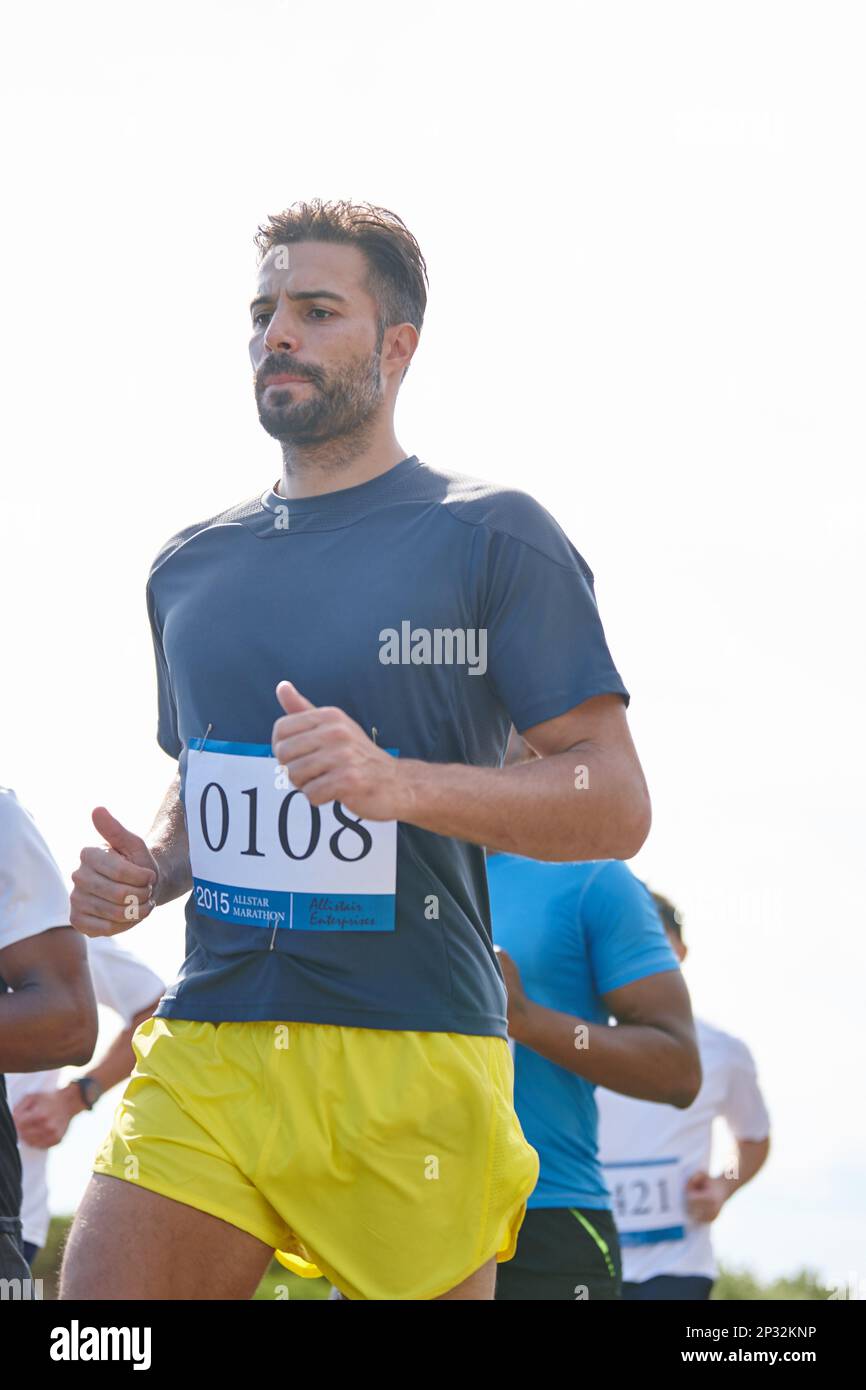 Run your own race. a young man running a marathon with other runners in ...