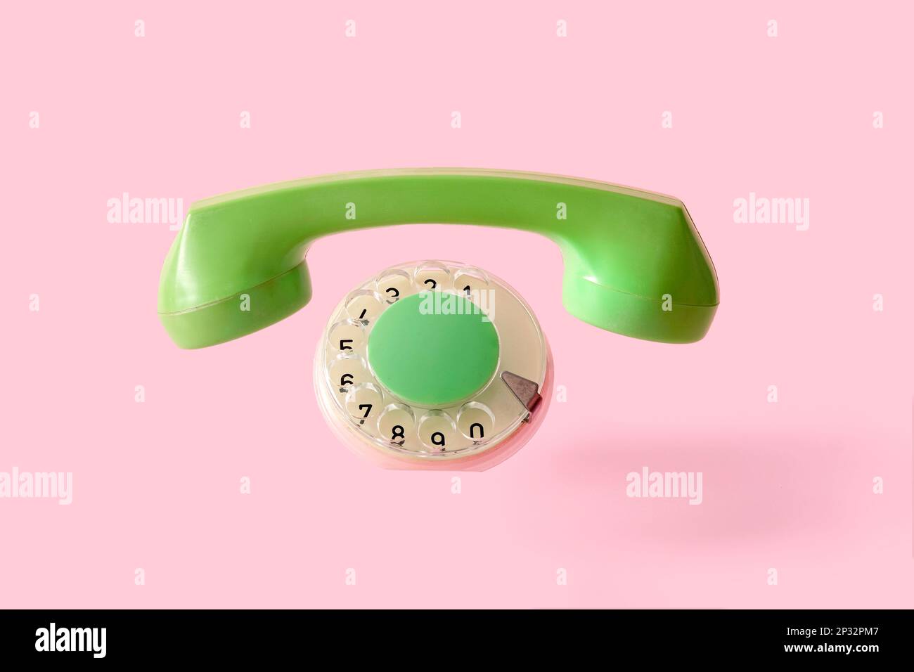 The handset and disc of an old retro phone on a pink background with ...