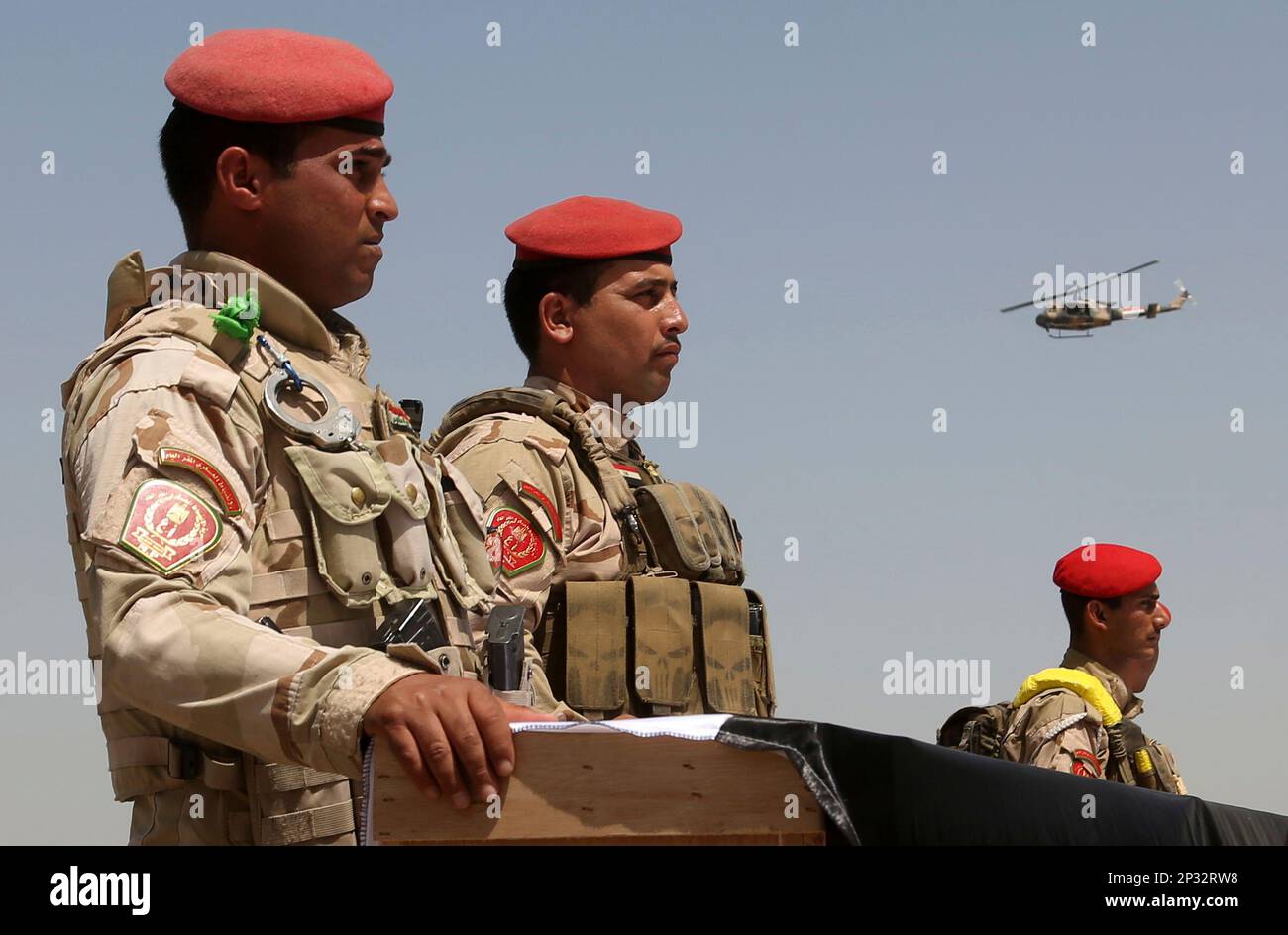 An Iraqi Army helicopter flies past as an honor guard stands during a ...