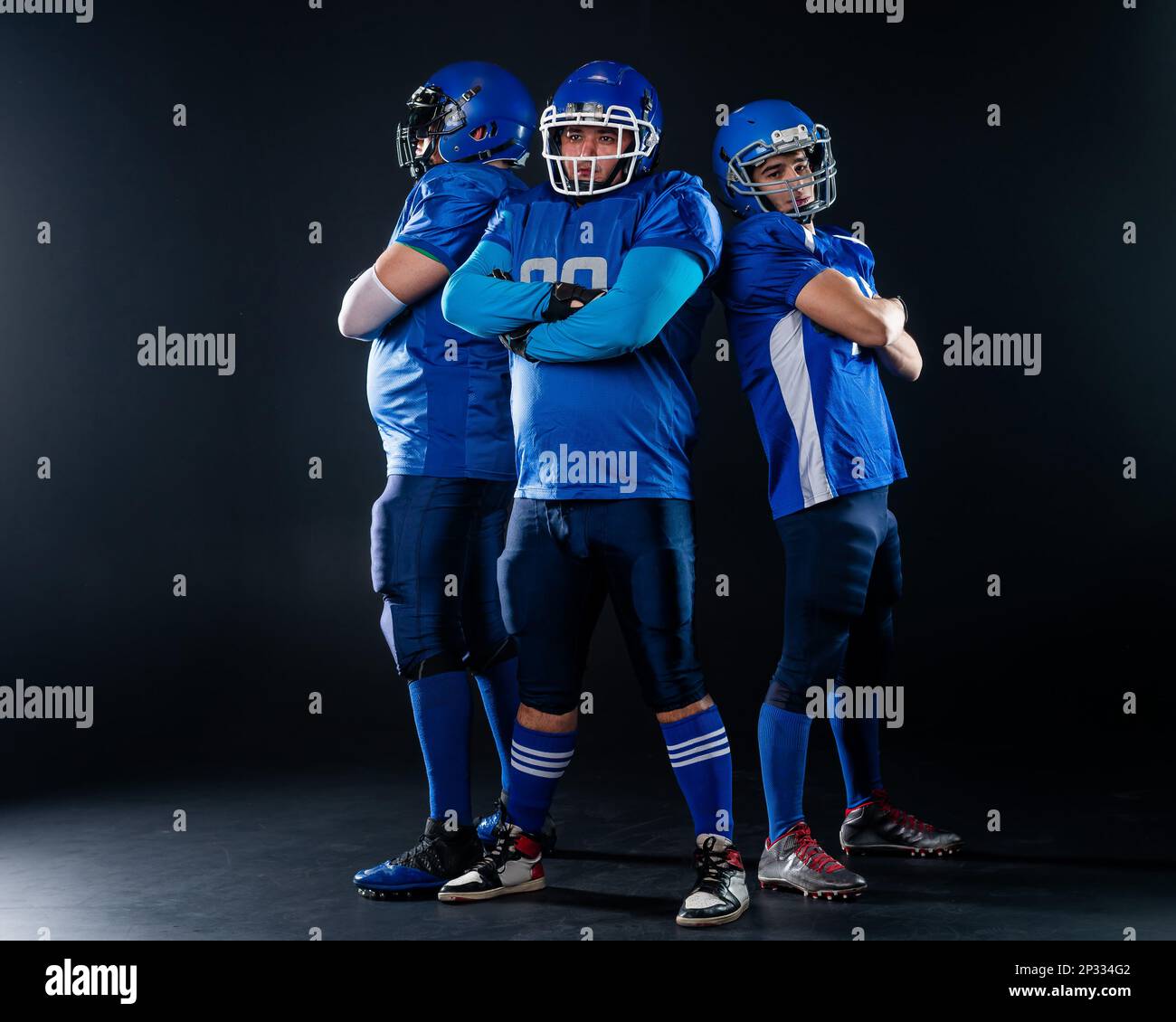 Portrait of three men in blue American football uniforms standing with ...