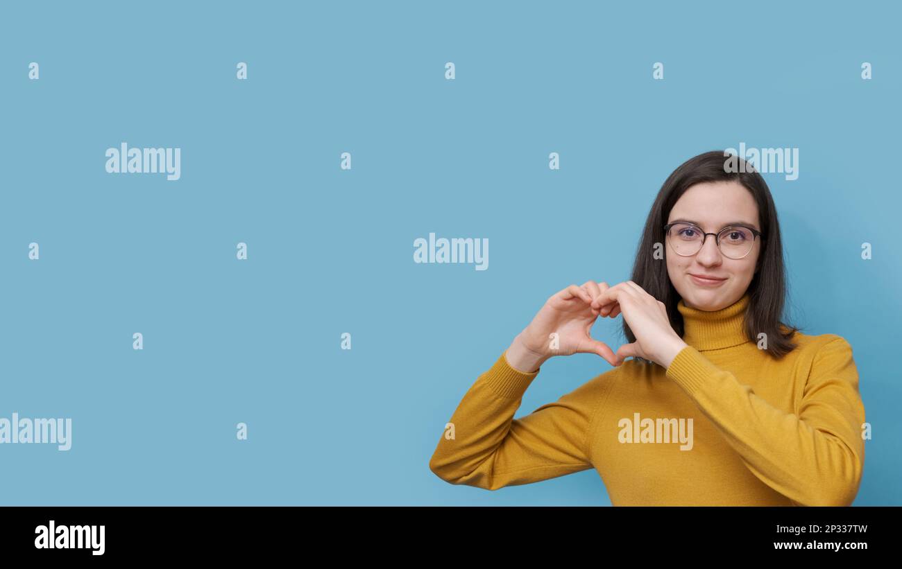 portrait beautiful student girl in glasses makes a heart shape with her ...