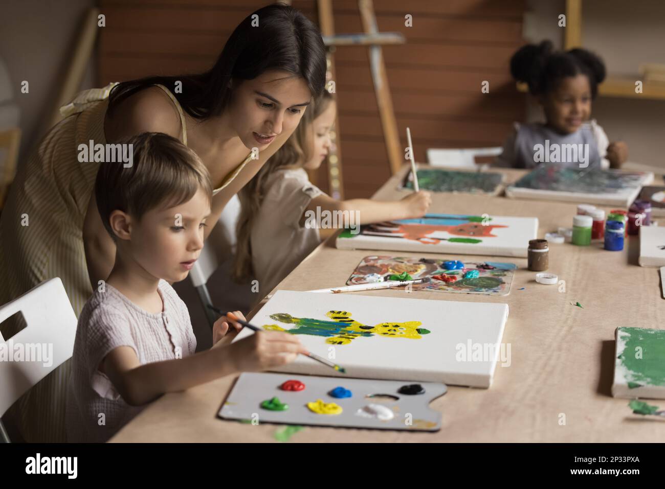 Friendly young art teacher giving artistic lesson to kids Stock Photo ...