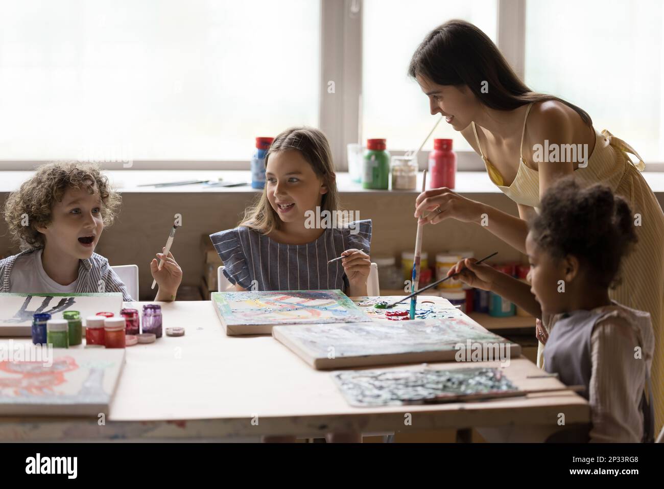 Happy pretty art school teacher giving lesson to pupil kids Stock Photo ...