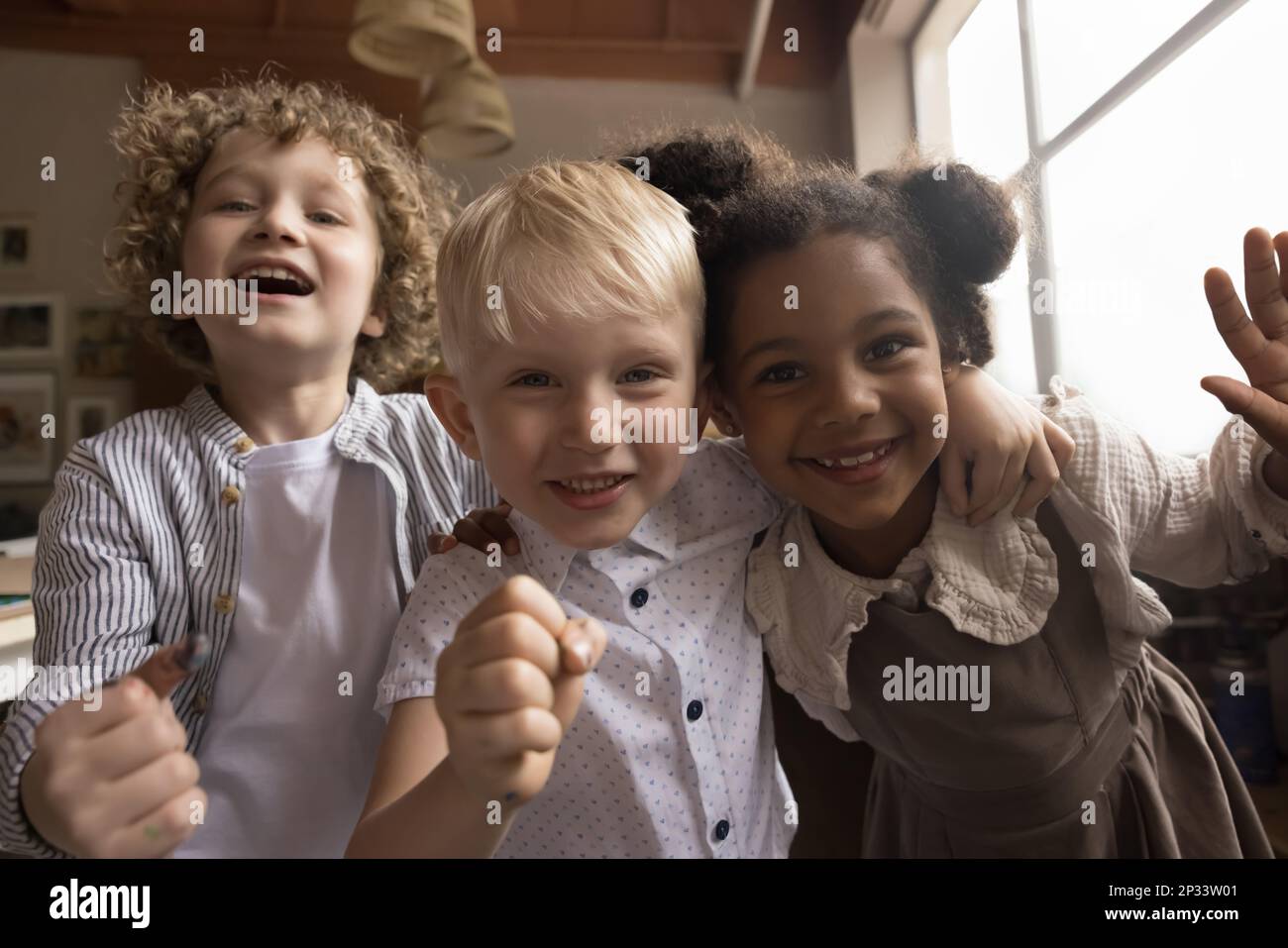 Cheerful diverse kids celebrating studying success, hugging in ...