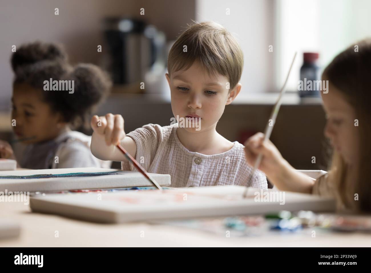 Focused cute kid drawing on class in group of classmates Stock Photo ...