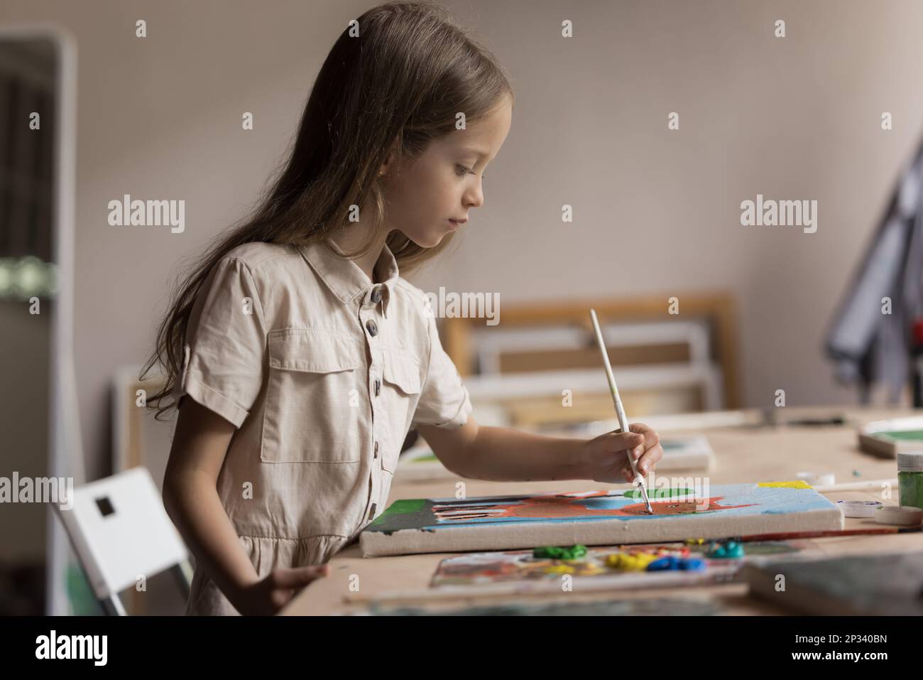 Focused pupil girl drawing on canvas at table in classroom Stock Photo ...