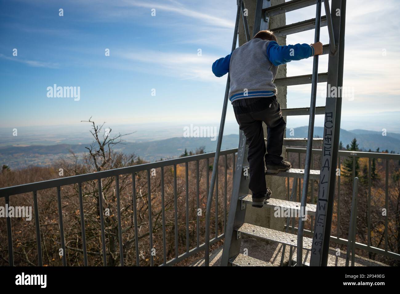 Little kid is going down the ladder of the dock tower. Fall season ...