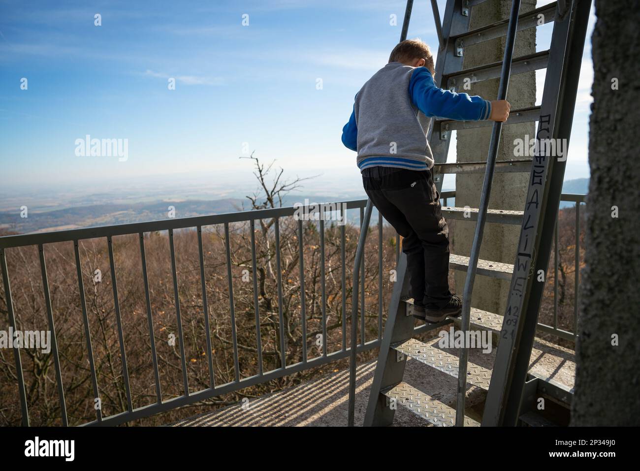 Little kid is going down the ladder of the dock tower. Fall season ...