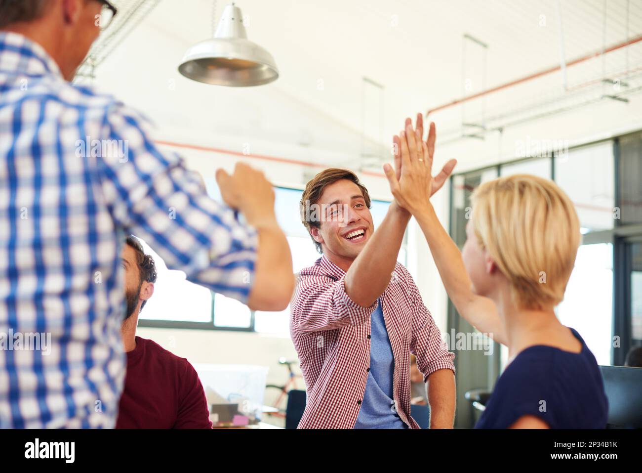 Winners never quit and quitters never win. a group of designer high-fiving each other during an ...