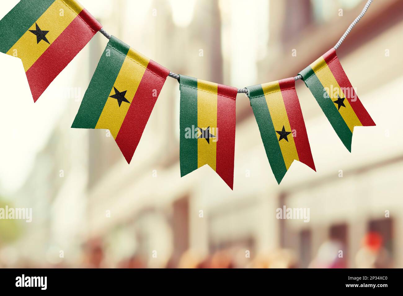 A garland of Ghana national flags on an abstract blurred background ...