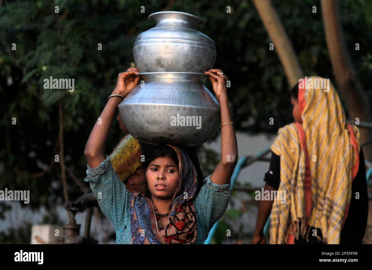 A Pakistani girl carries clean water to her home in Lahore's slums in ...