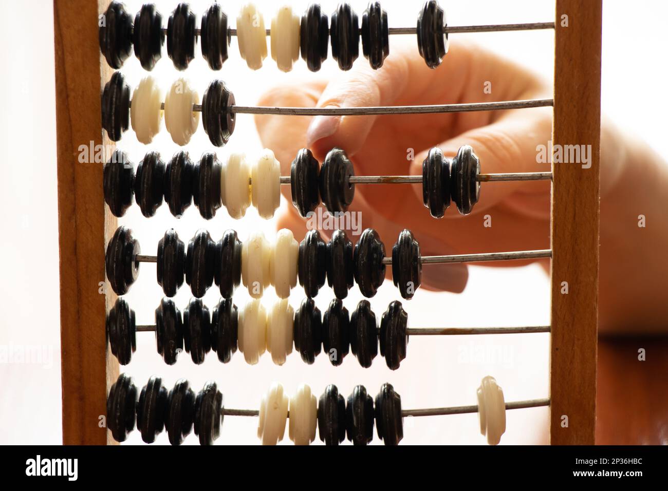 Old wooden abacus for counting money and a woman's hand on a bright ...