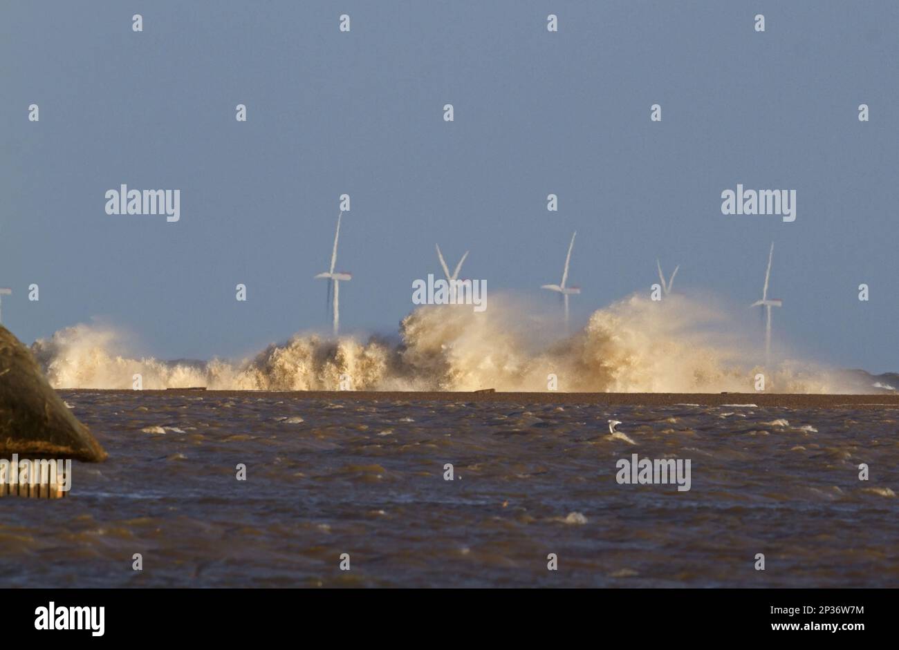Waves crashing against remains of shingle sea defences, with flooded ...
