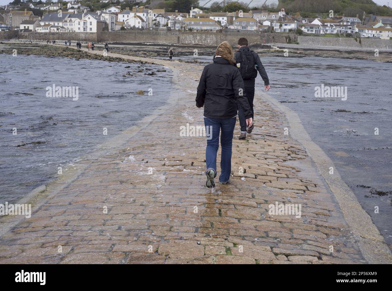 Tourists walking in the sea water covering the man-made causeway from ...
