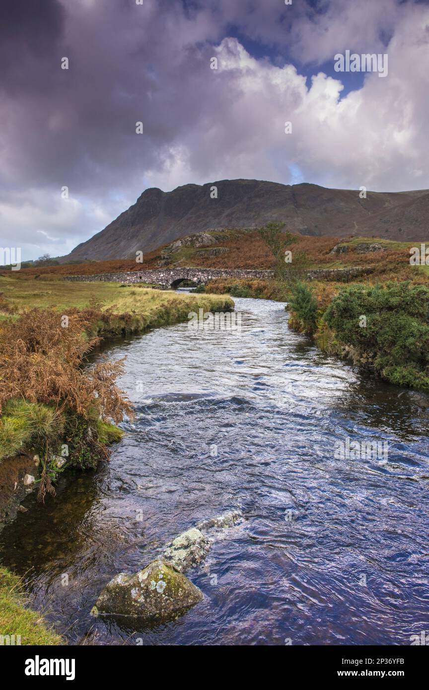 View of river and bridge in upland valley, with Seatallan Peak in ...