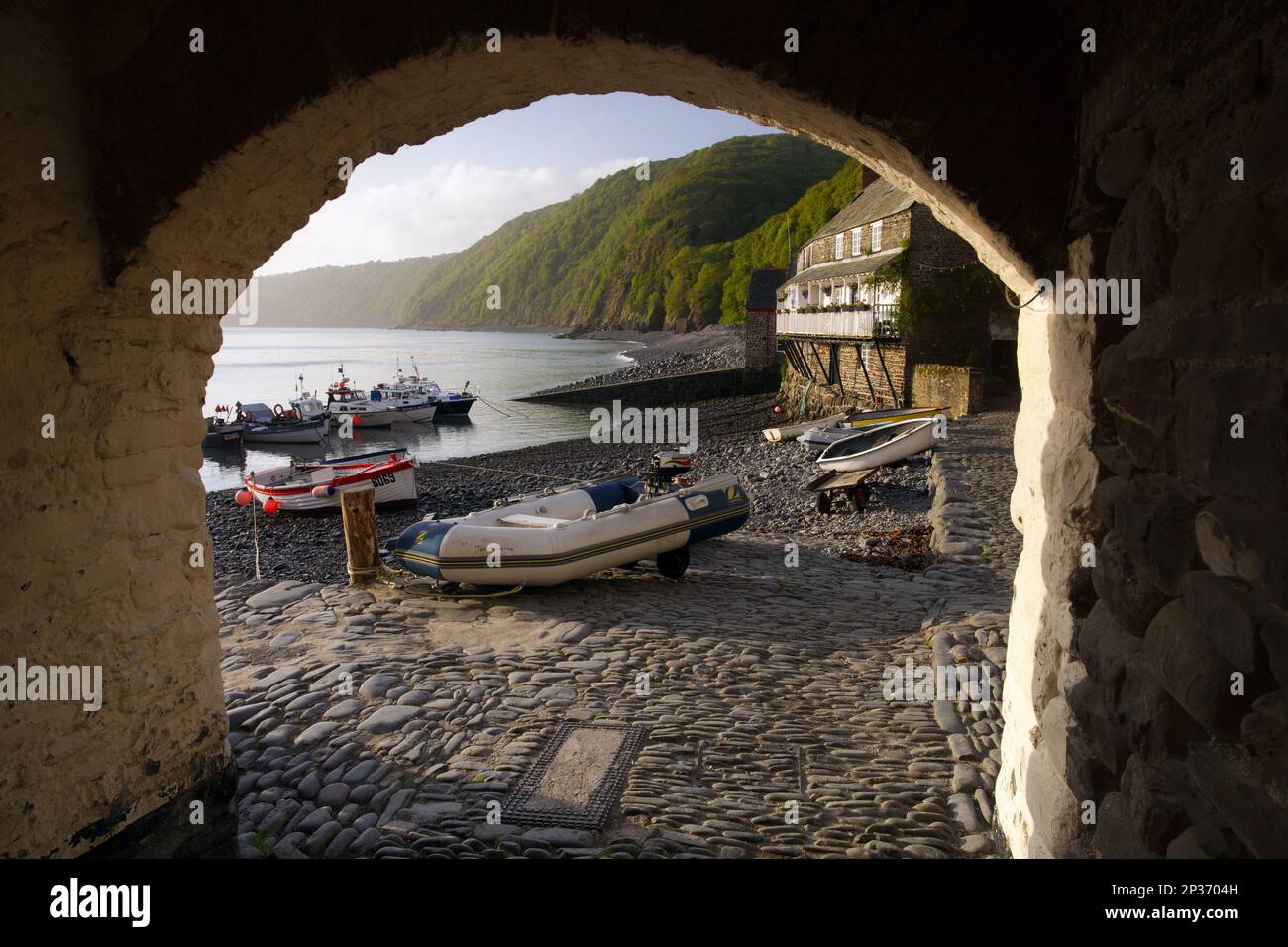View through archway of fishing boats and wharf houses at dawn ...
