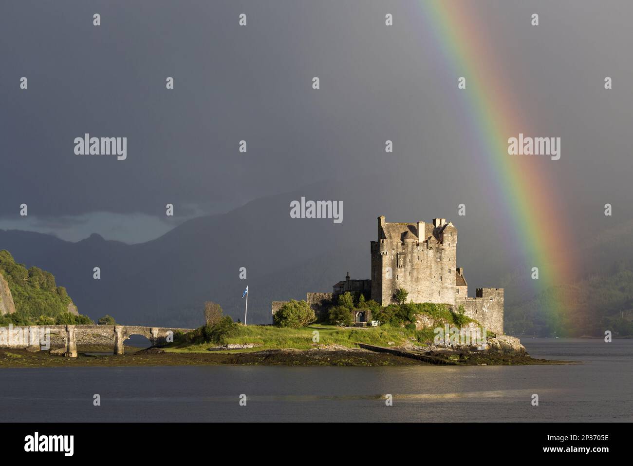 View of restored castle on tidal island in sea loch with rainbow, in ...